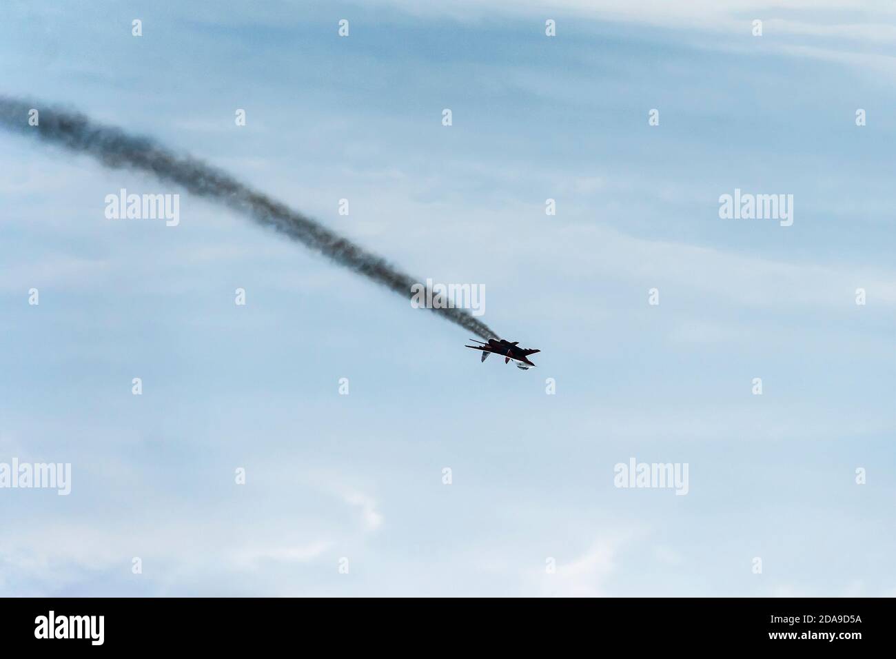 Military fighter jet during a fall on the background of blue sky. The ...