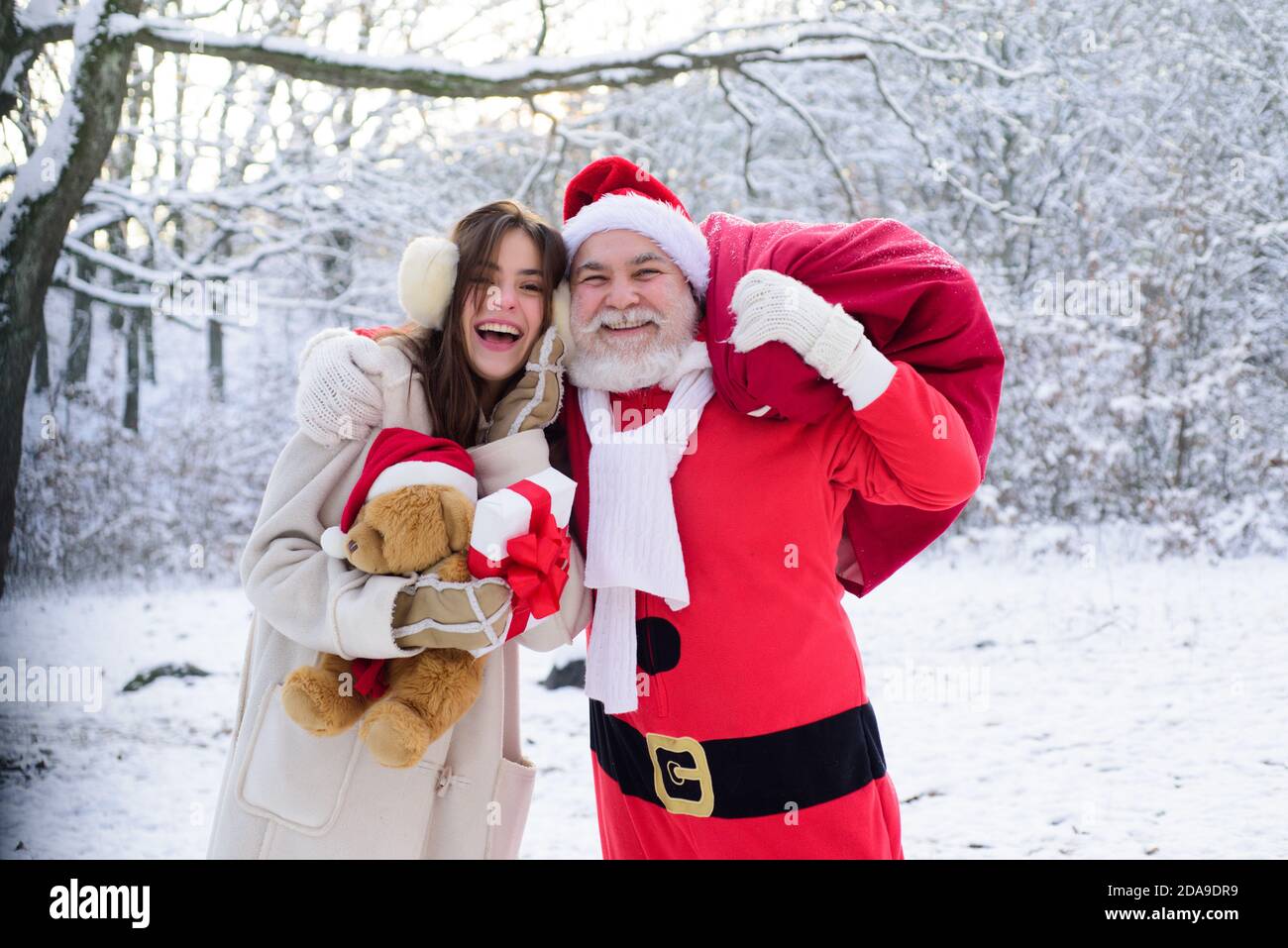 Santa Claus and girl with presents in snowy forest. Daughter and father ...