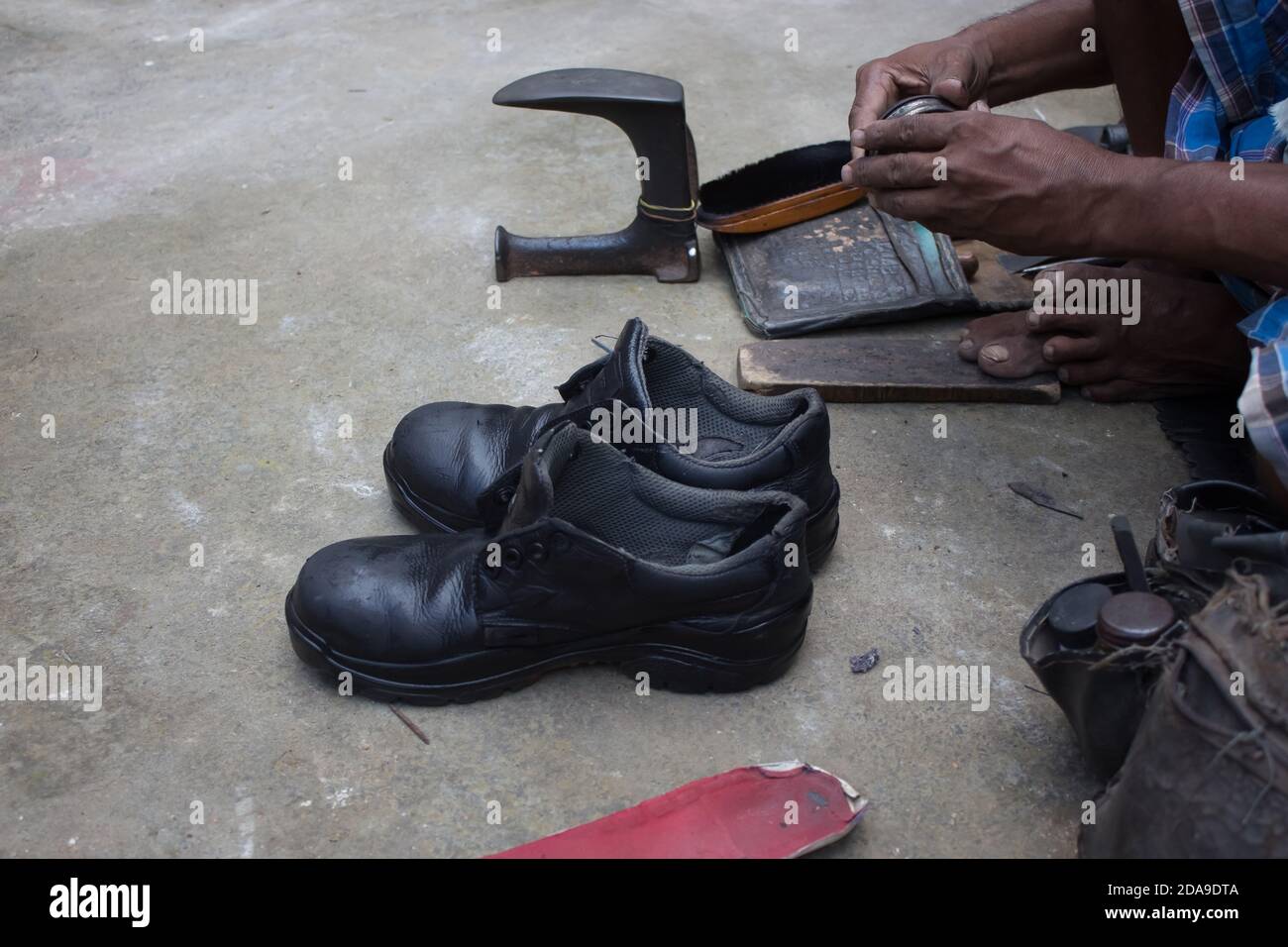 Indian local cobbler repairing shoes beside road by hand using tools in ...