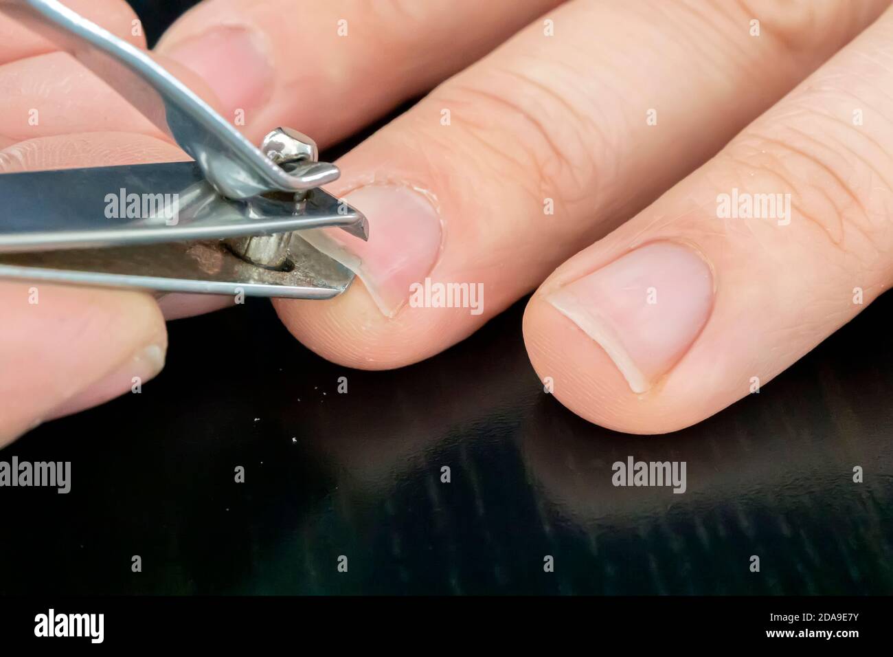 hand manicure with nail clipper. close up over black background. self ...