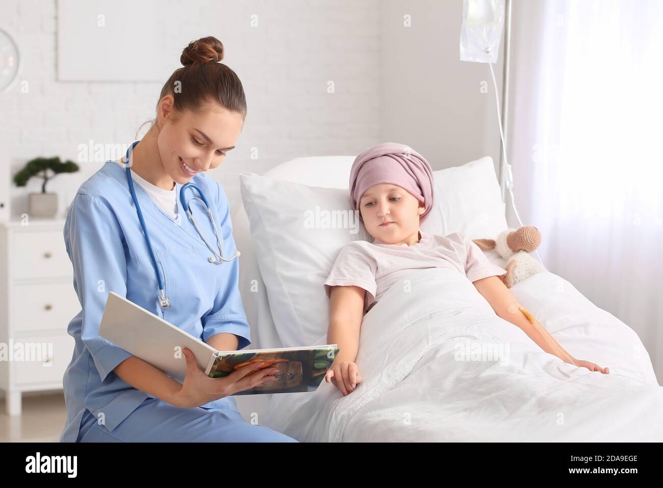 Nurse reading book to little girl undergoing course of chemotherapy in ...