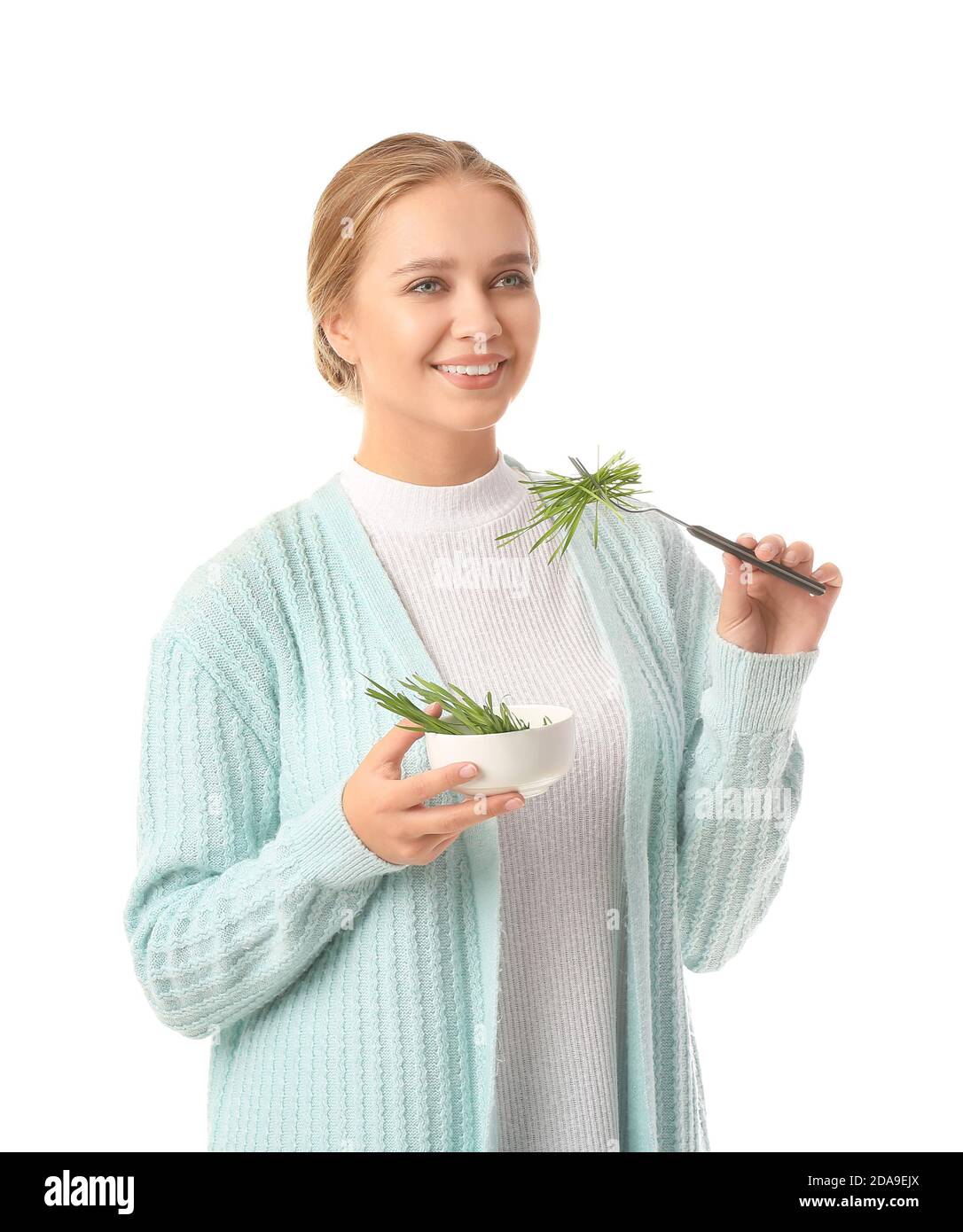 Young woman eating wheatgrass on white background Stock Photo - Alamy