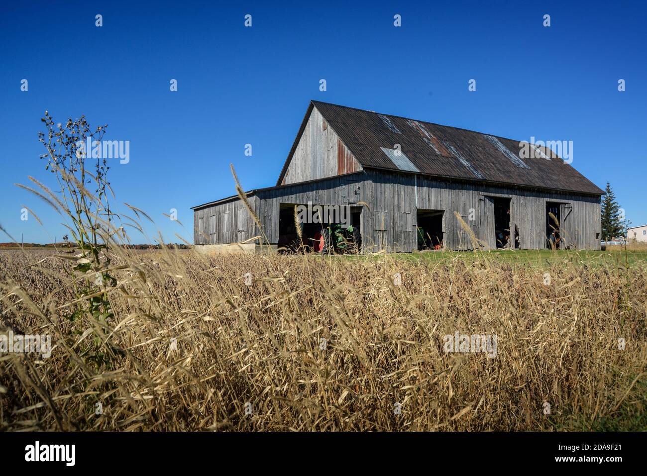 Old wooden grey plank barn for storing tractors and farm equipment ...