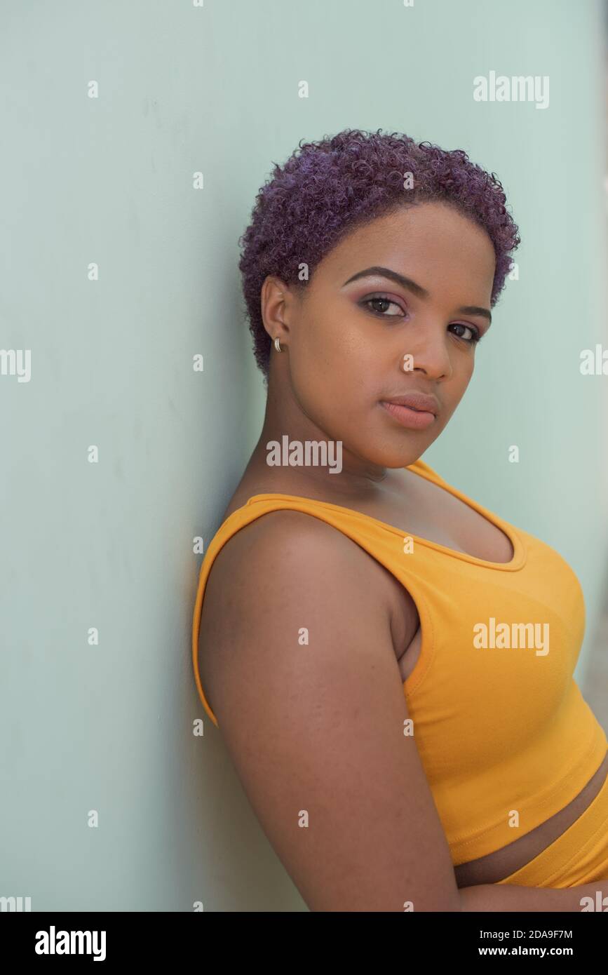 Beautiful young woman leaning against wall Stock Photo - Alamy