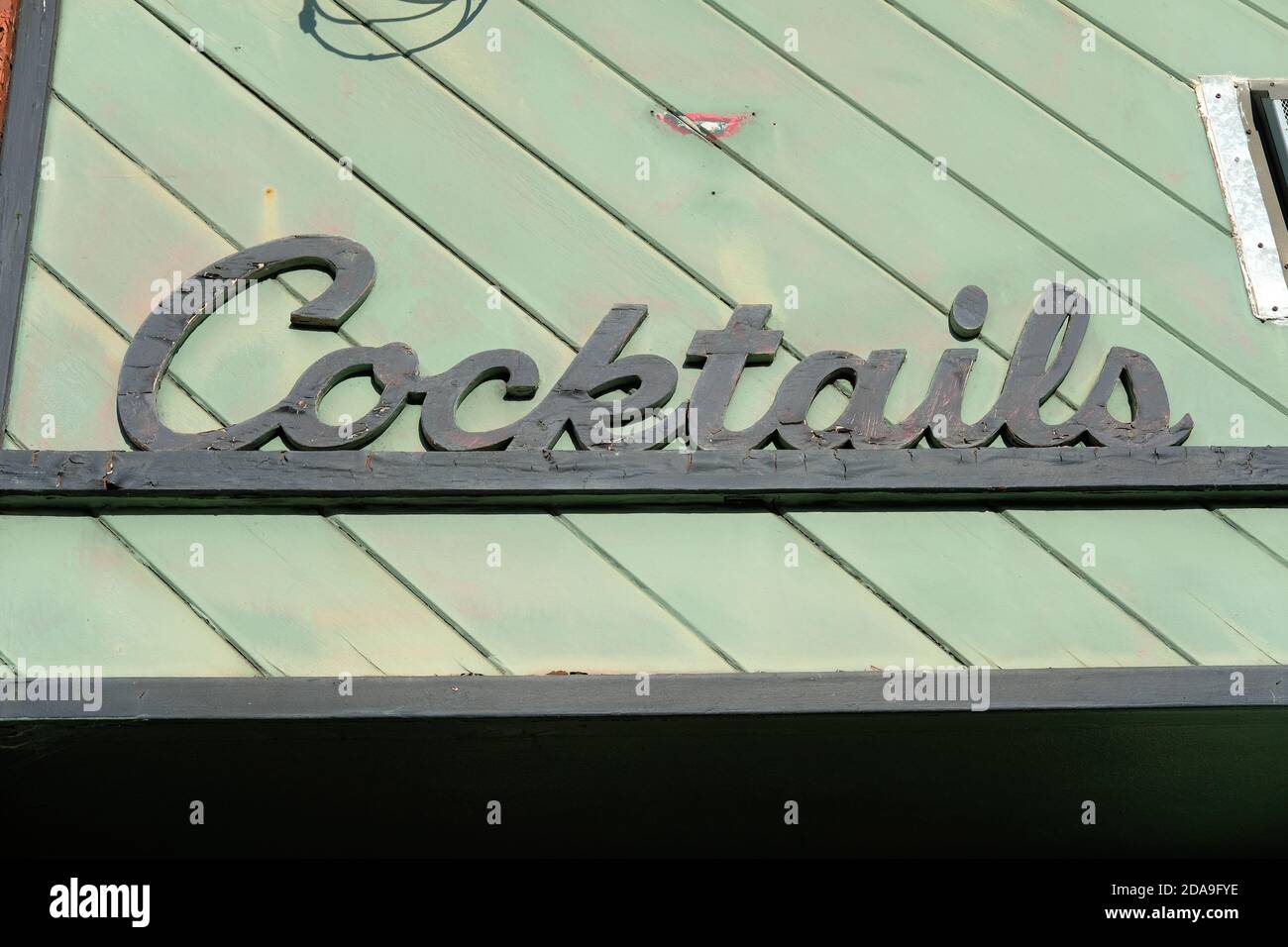 Cocktails sign in cursive script over a closed bar that is no longer ...