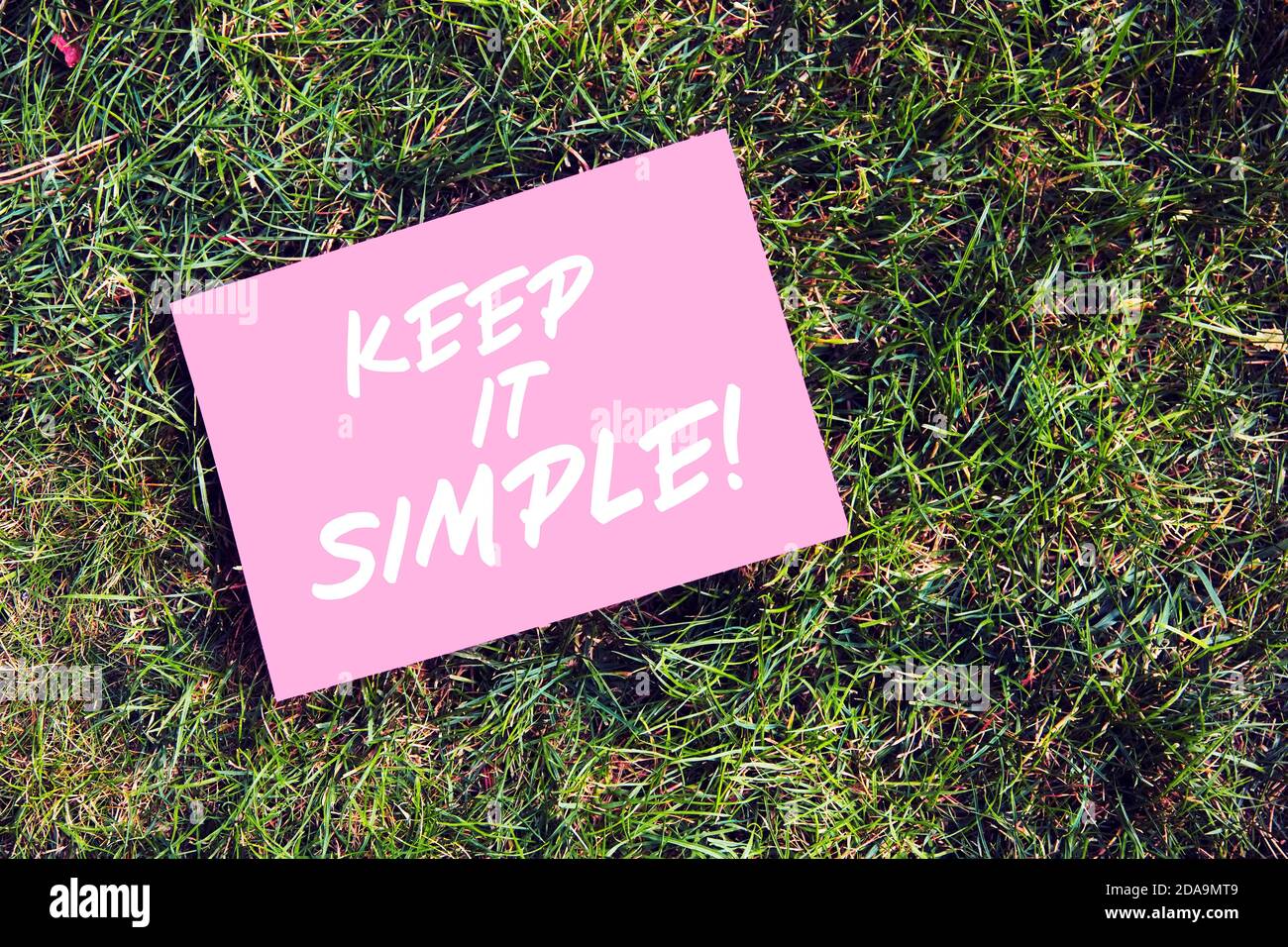 Keep it simple motivational quote written on pink paper on green grass ...
