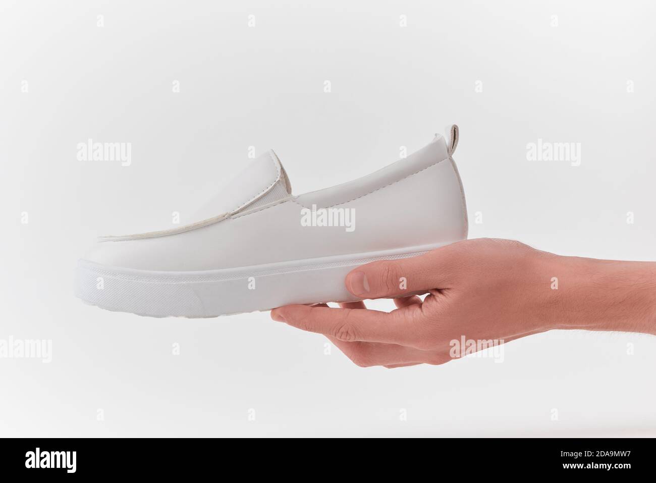 Hand holding a white leather slip-on shoe Stock Photo - Alamy