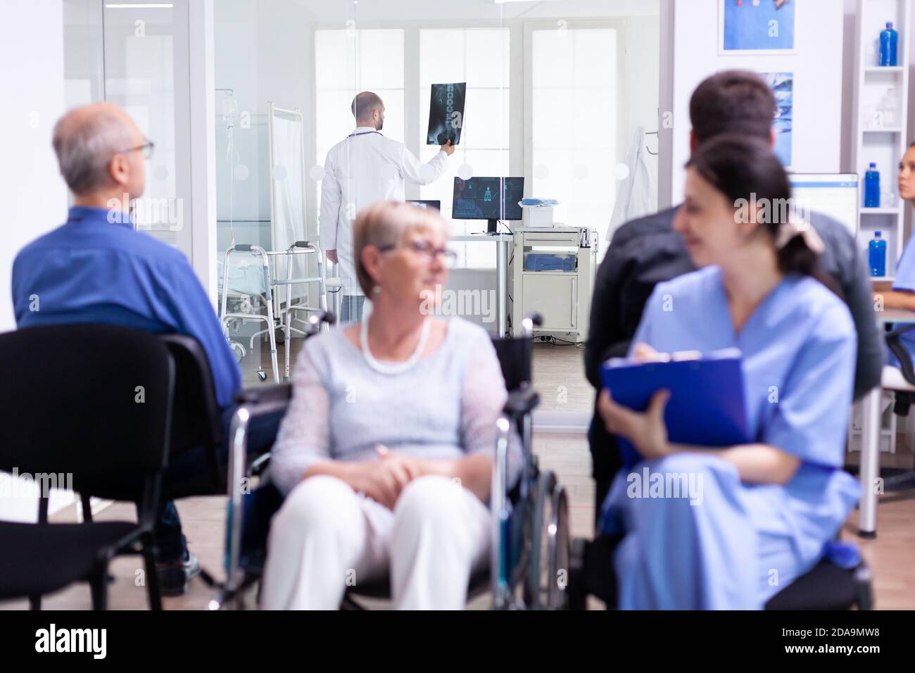 Nurse filing documents while talking with disabled senior woman in ...