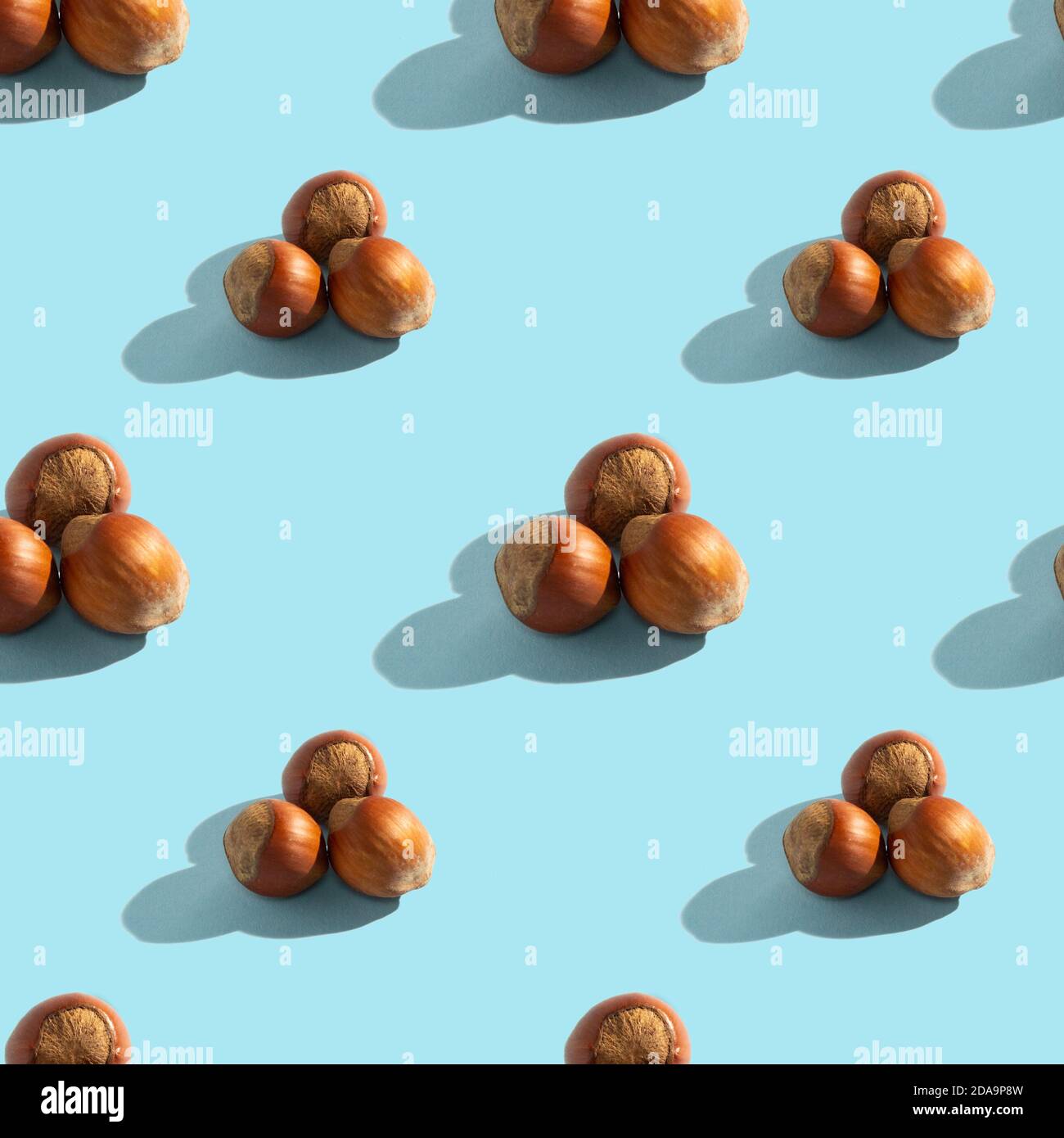 Whole hazelnuts with a shadow on a blue background, seamless pattern ...