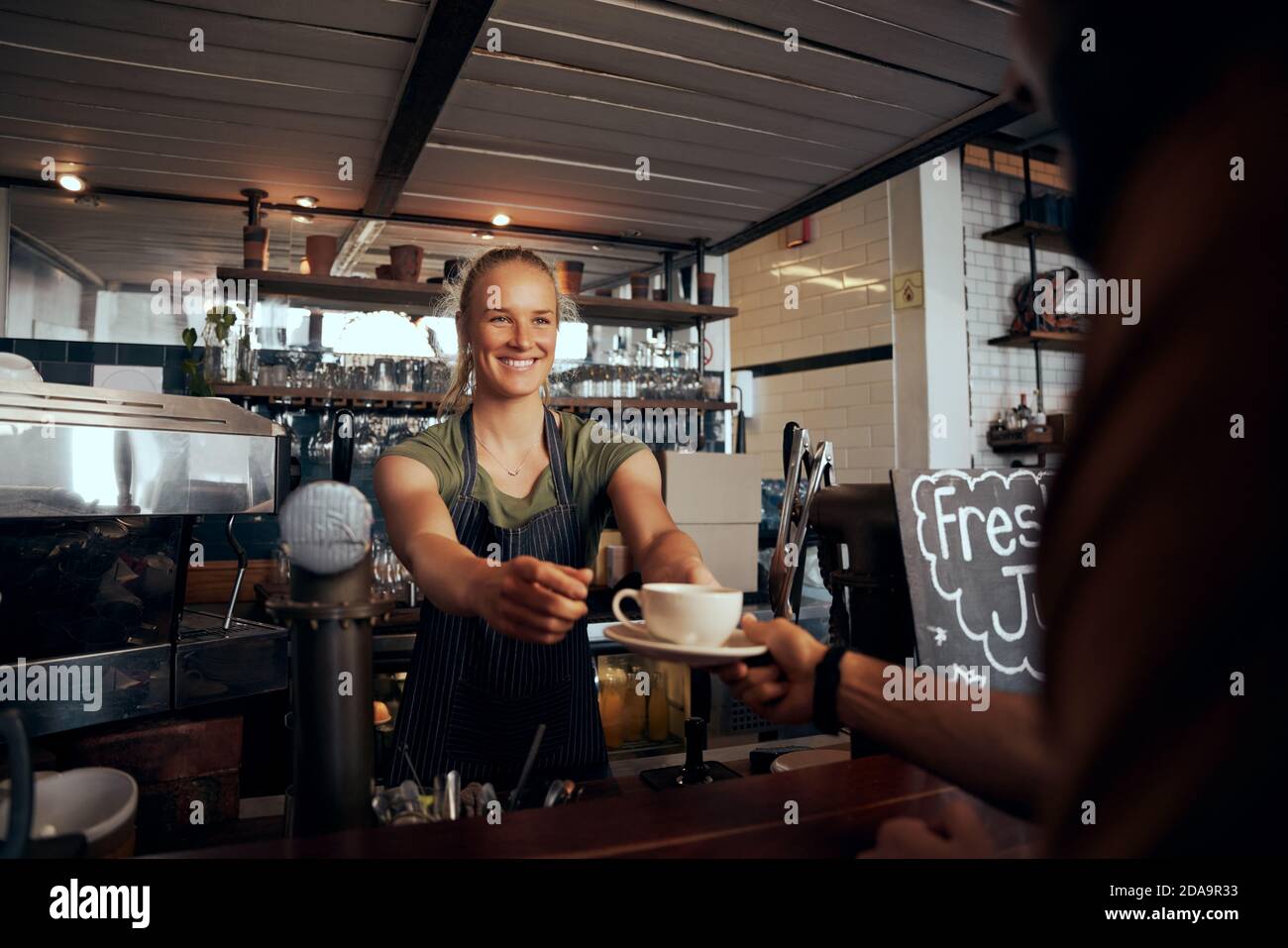 Beautiful young female waiter serving cup of coffee to customer in ...
