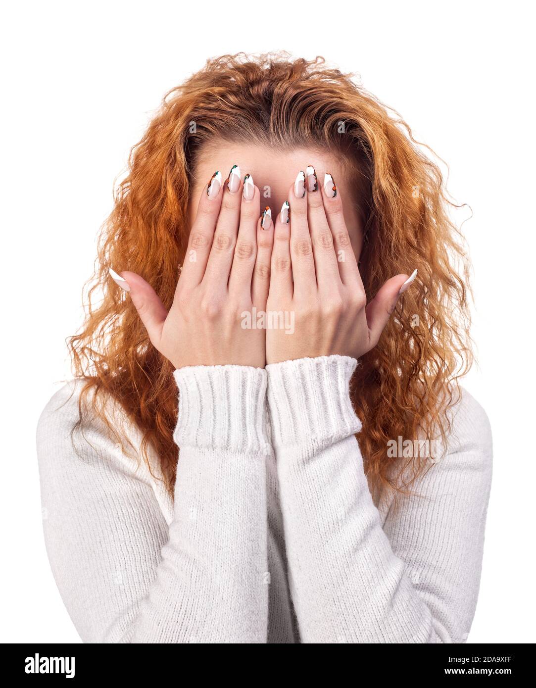 Portrait of red-haired woman covering her face by the hands, over white ...