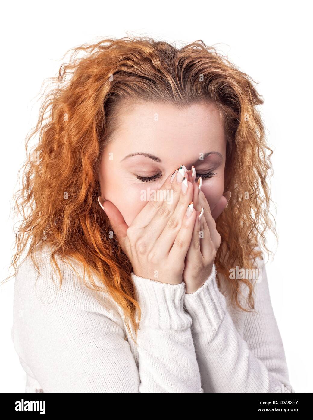 Portrait of red-haired woman covering her face by the hands, over white ...