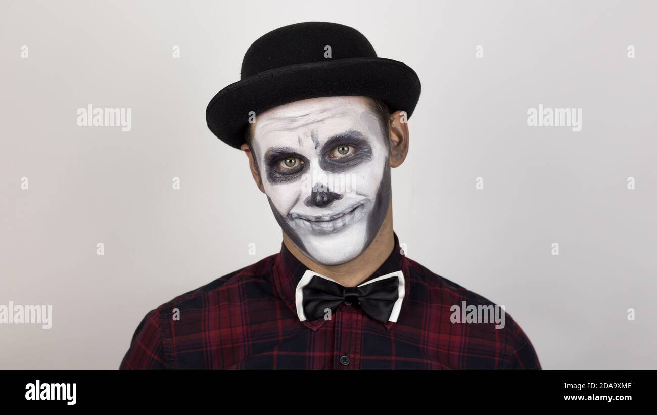 A scary clown looks at the camera and laughs terribly. Scary grimaces ...