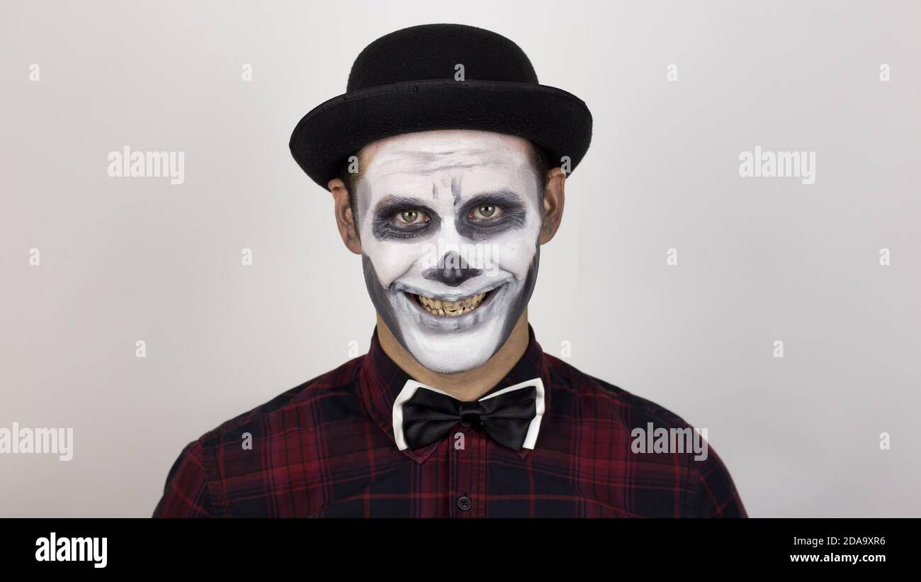 A scary clown looks at the camera and laughs terribly. Scary grimaces ...