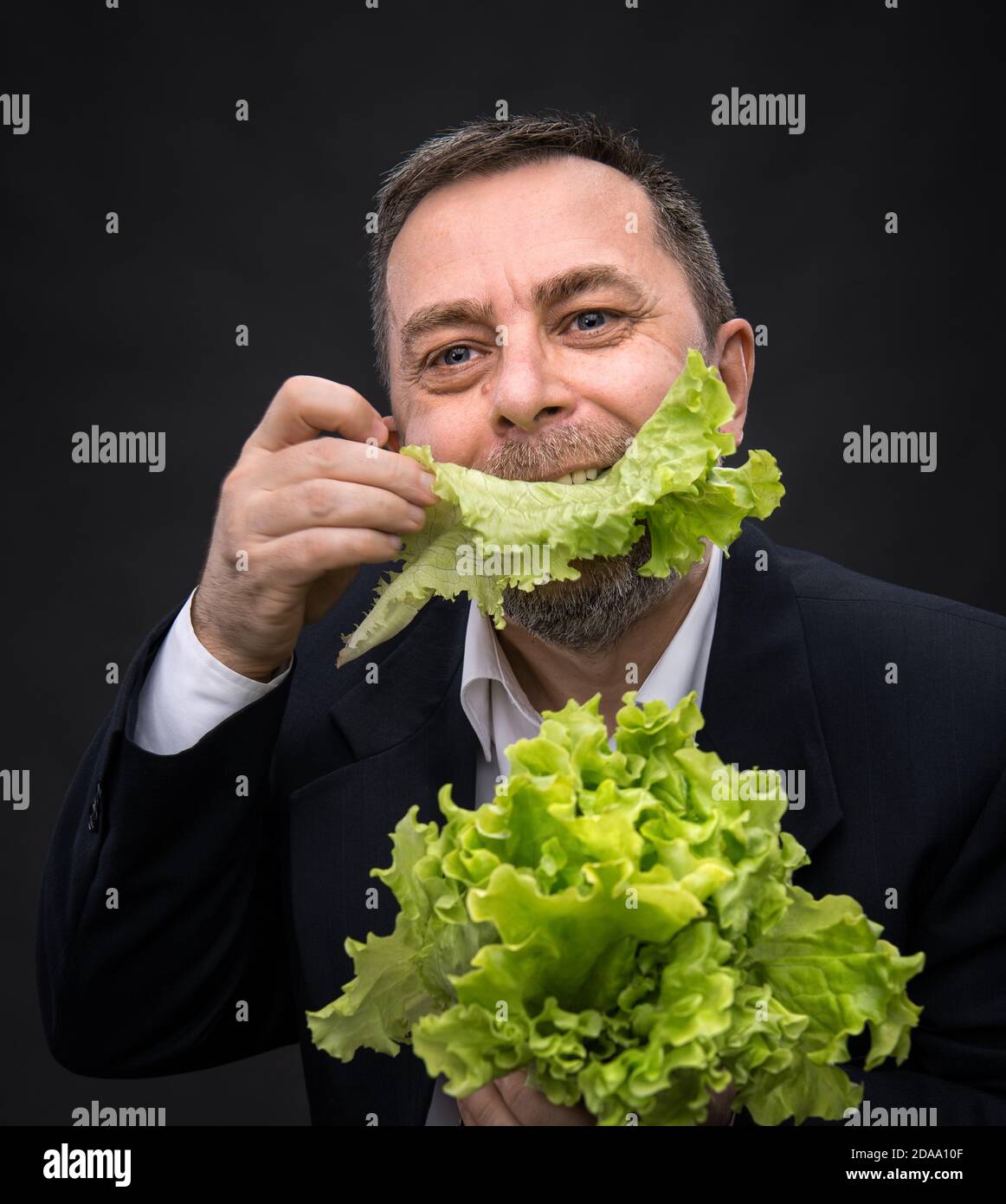 Organic food. Man holding and eating lettuce Stock Photo - Alamy
