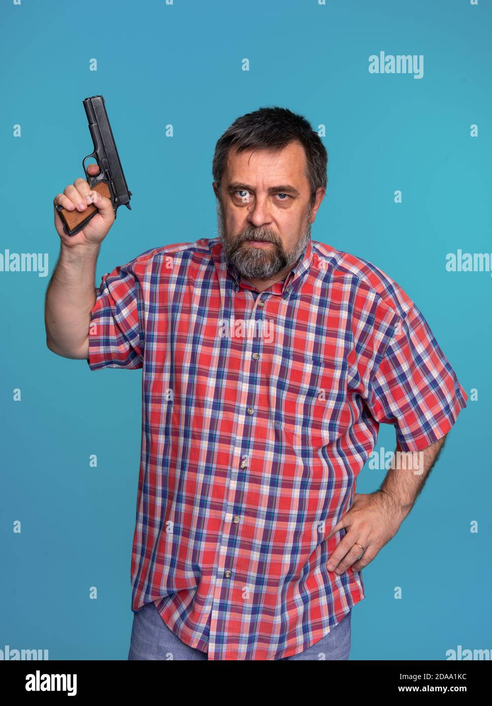 Portrait of a handsome man holding a gun. Bearded middle-aged man is ...