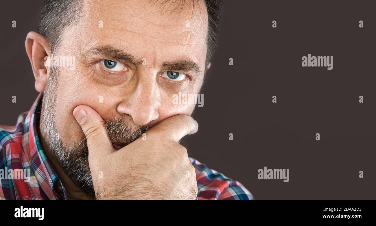 Close-up portrait portrait of a thoughtful elderly man with hand near ...