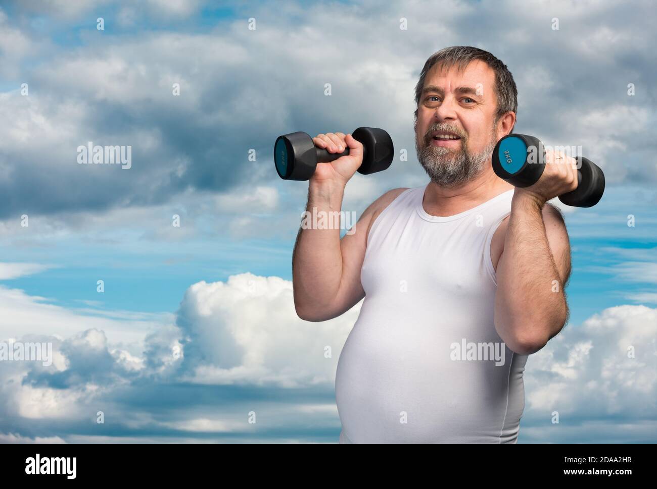 Middle-aged man with a paunch exercising with dumbbells on cloudy sky ...