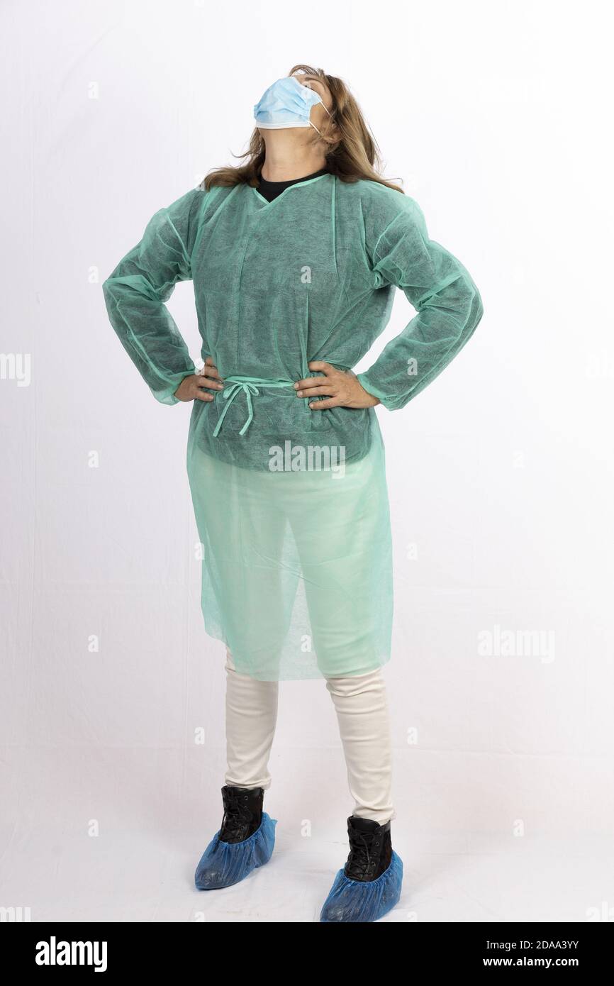 Woman wearing a surgical gown, face mask, shoe covers looking up ...