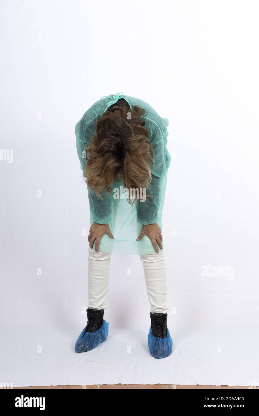 Woman wearing a surgical gown and shoe covers bowing on her knees Stock ...