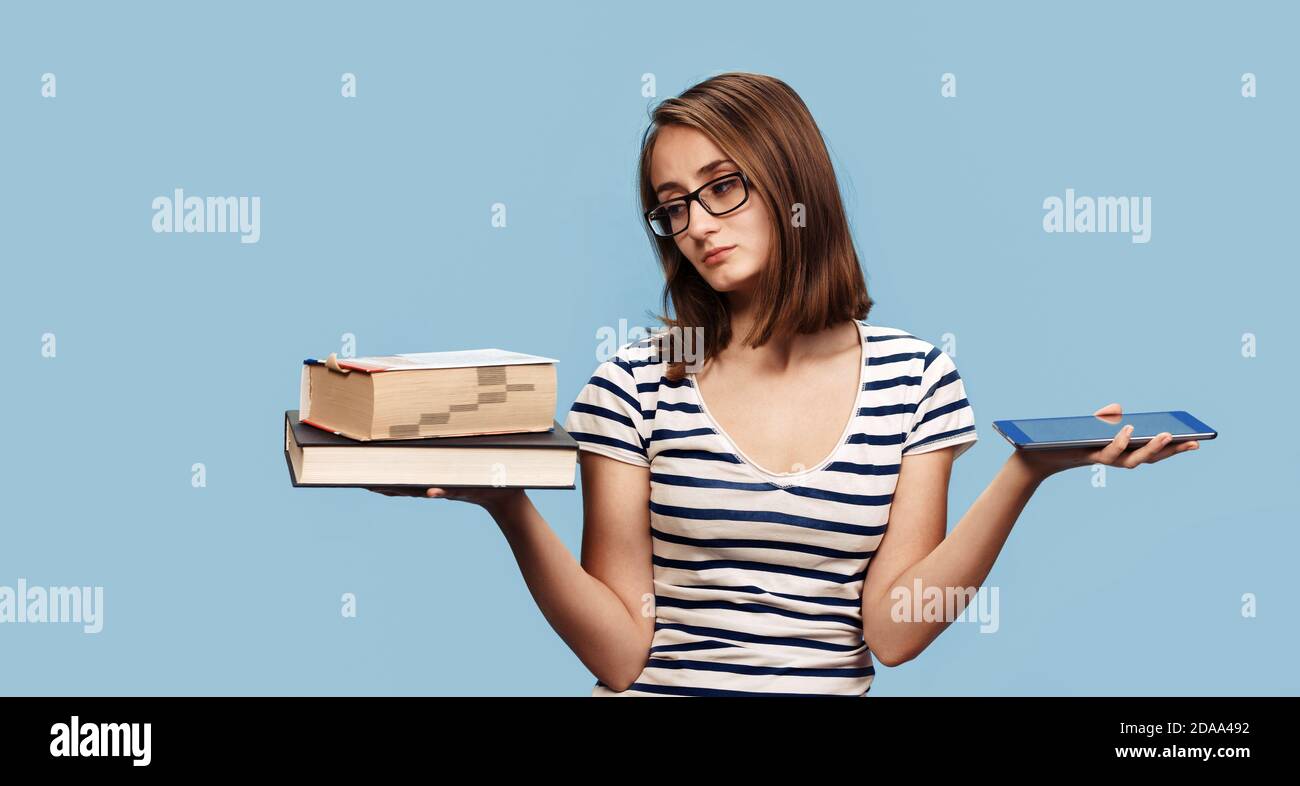 Contemporary education concept. Book vs e-book. Girl student holding ...
