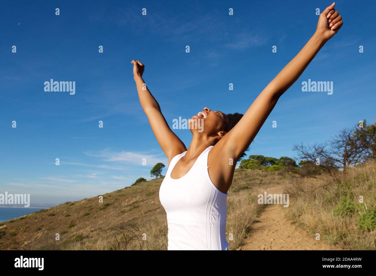Portrait of overjoyed african woman standing outdoors with her arms ...