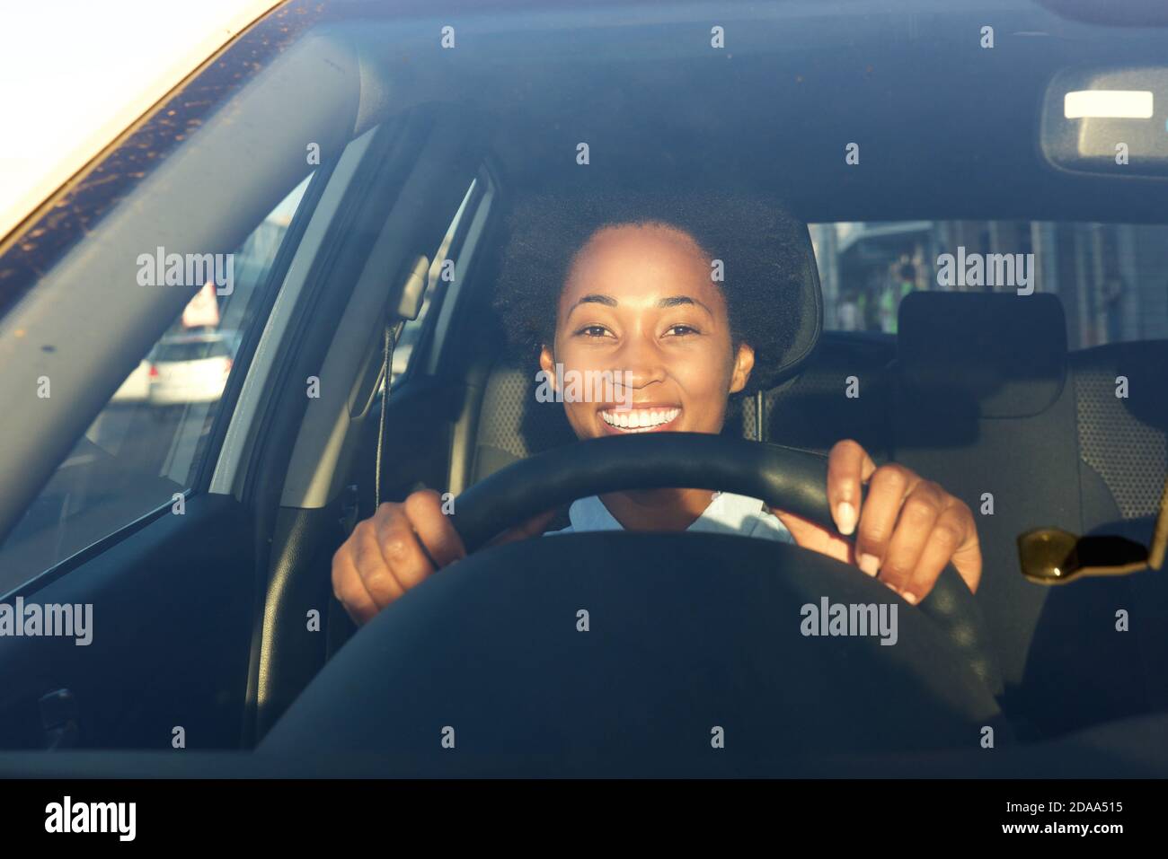 Portrait of happy young african american woman driving a car and ...