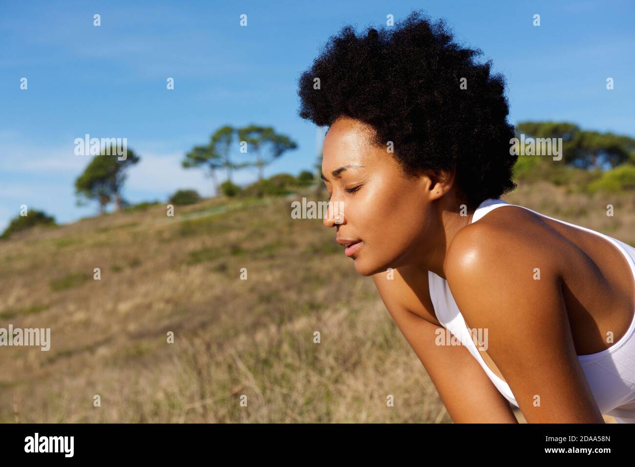 Side portrait of young african female runner having break during the ...
