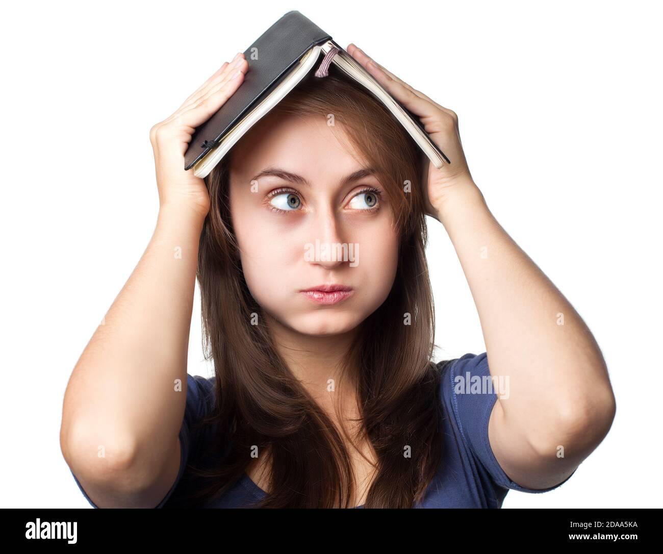 Education. Tired girl holds a notebook on her head on a white ...