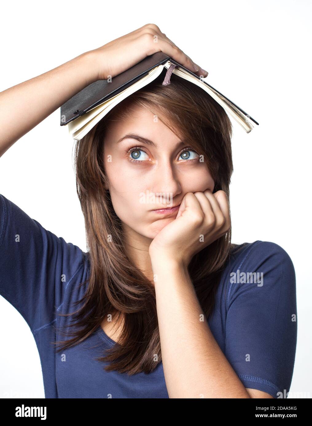 Education. Tired girl holds a notebook on her head on a white ...