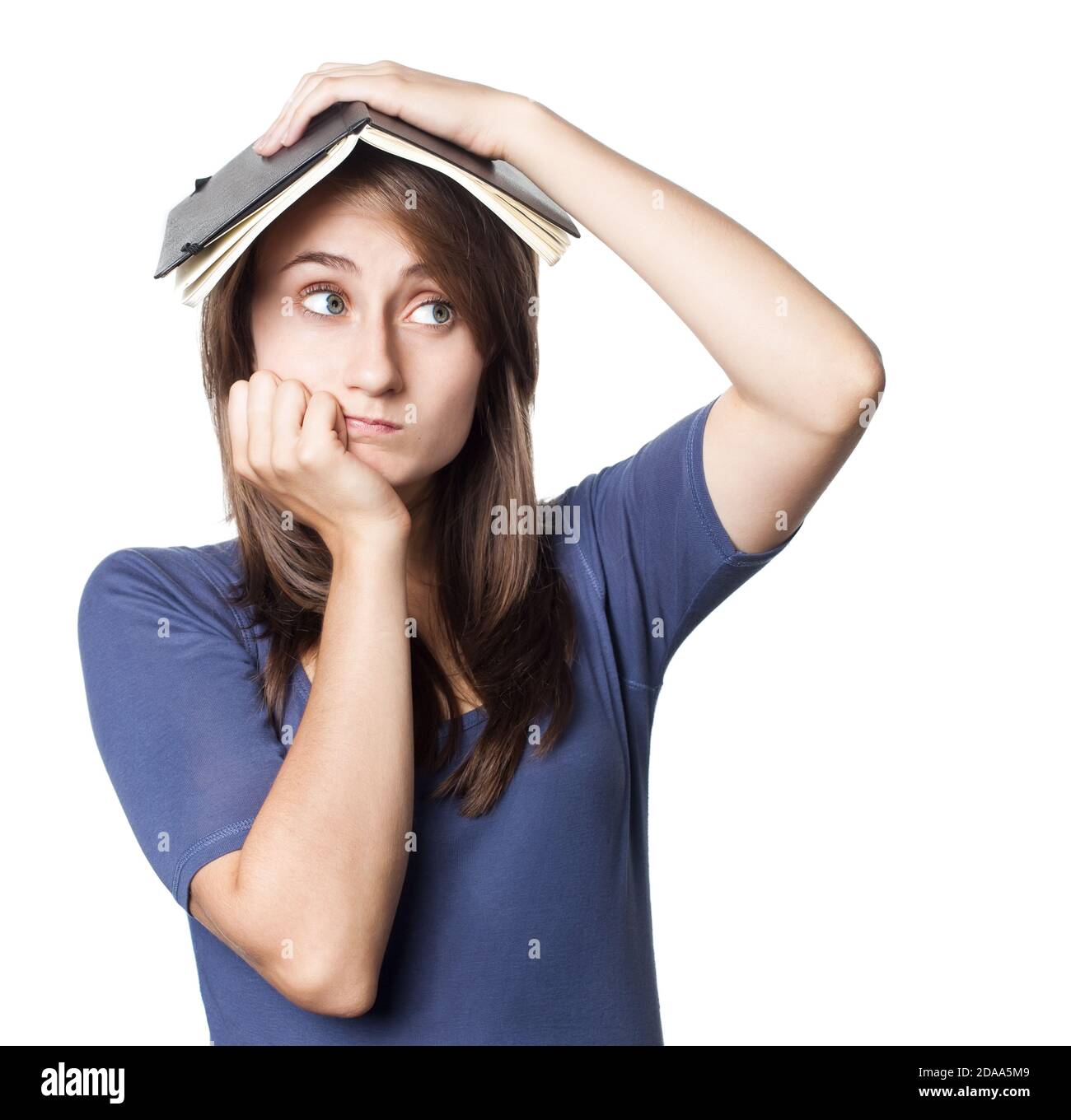 Education. Tired girl holds a notebook on her head on a white ...