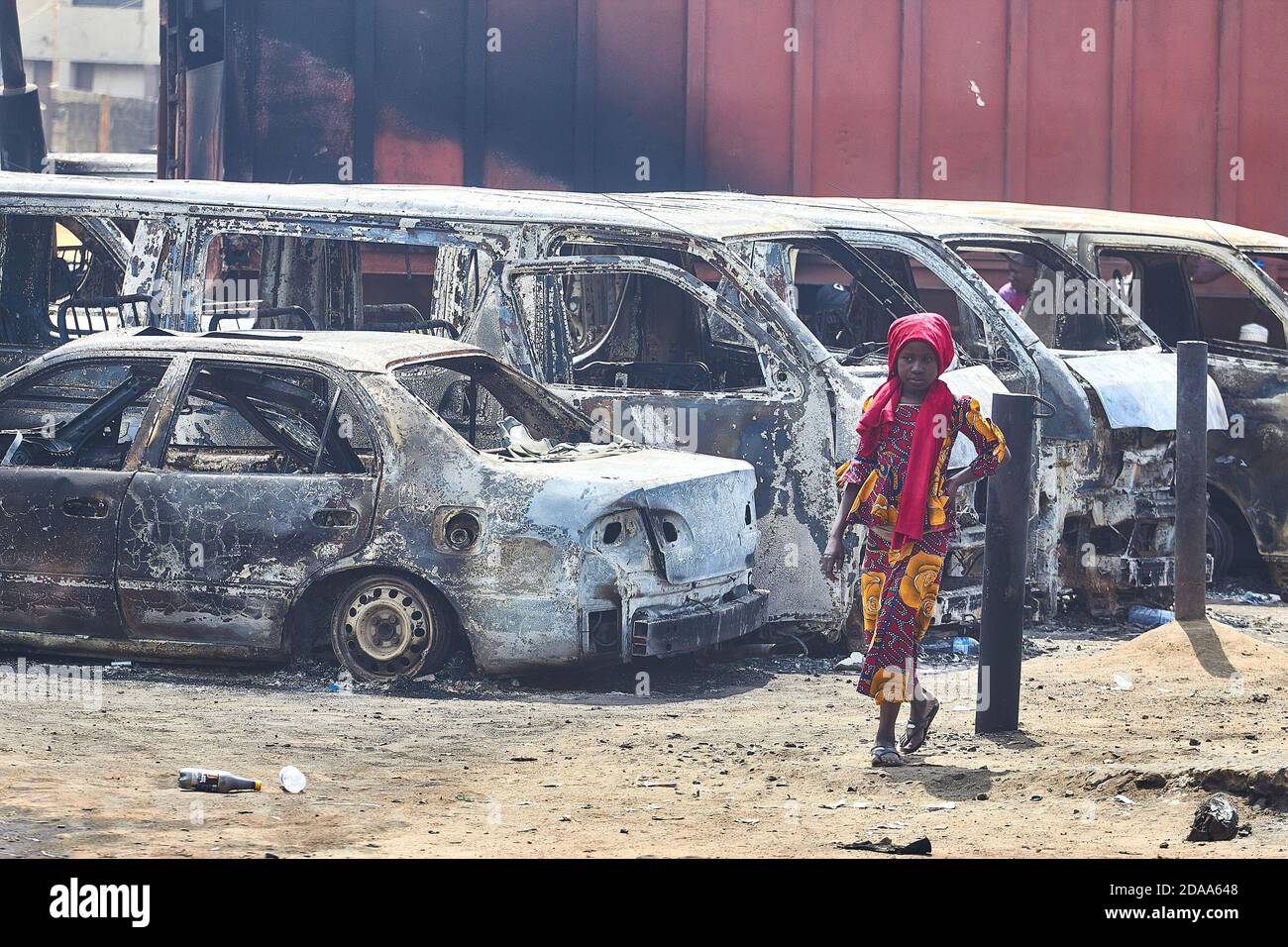 A girl walks by damaged vehicles at a site following an explosion after ...