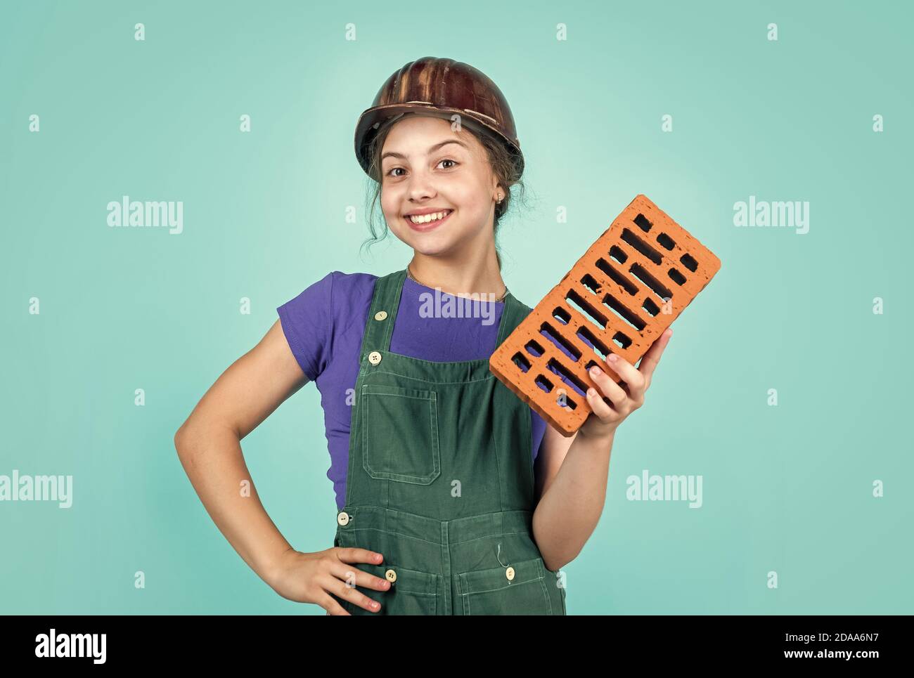 International workers day. girl in helmet plays builder with brick ...