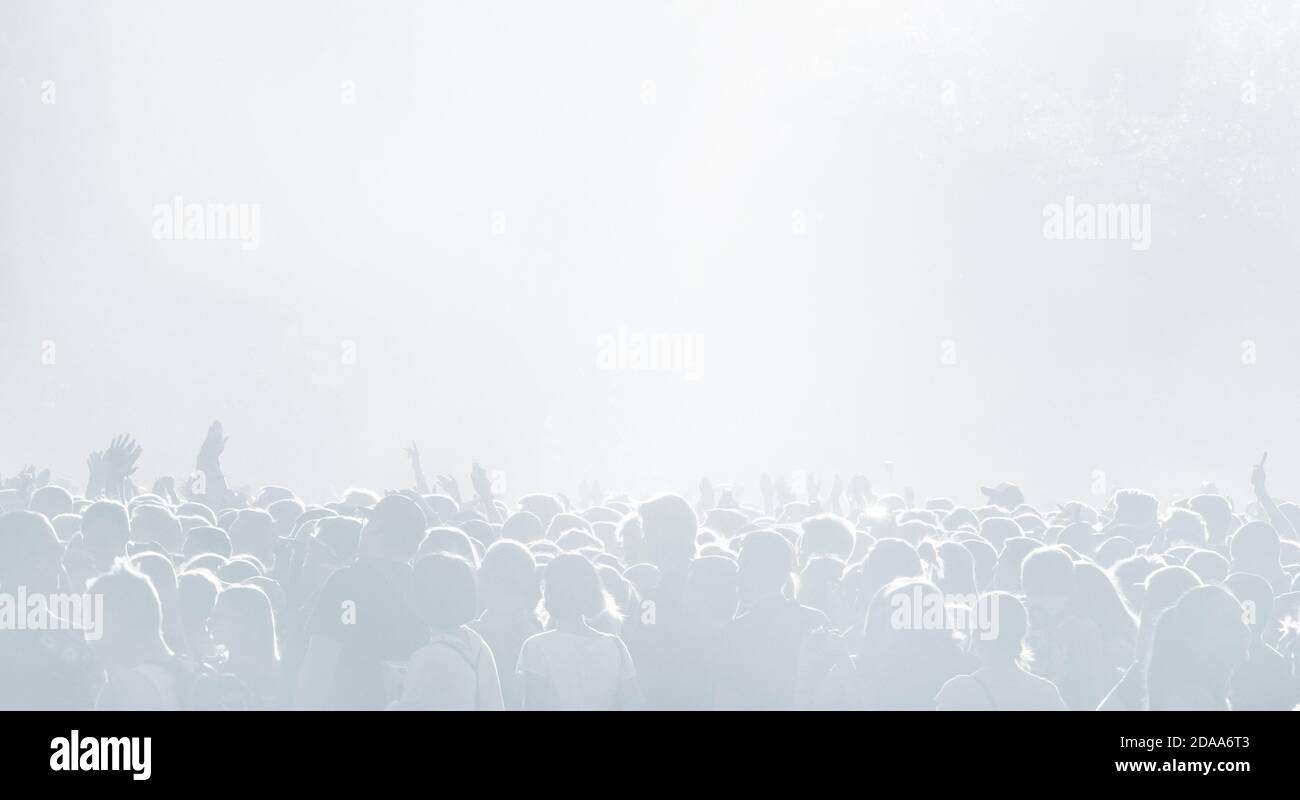 Crowd of spectators at a concert in light blue tonality. High key ...