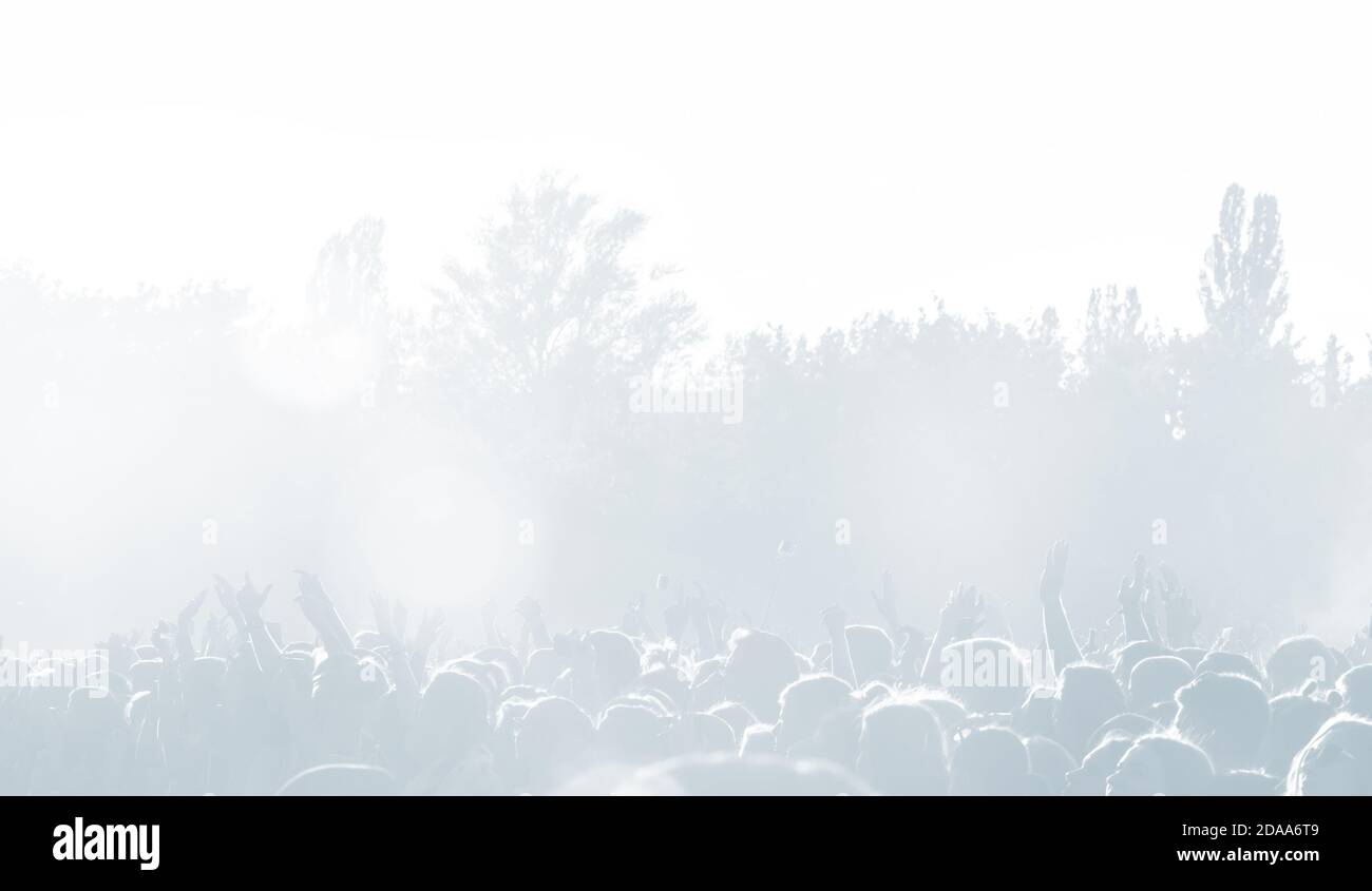 Crowd of spectators at a concert in light blue tonality. High key ...
