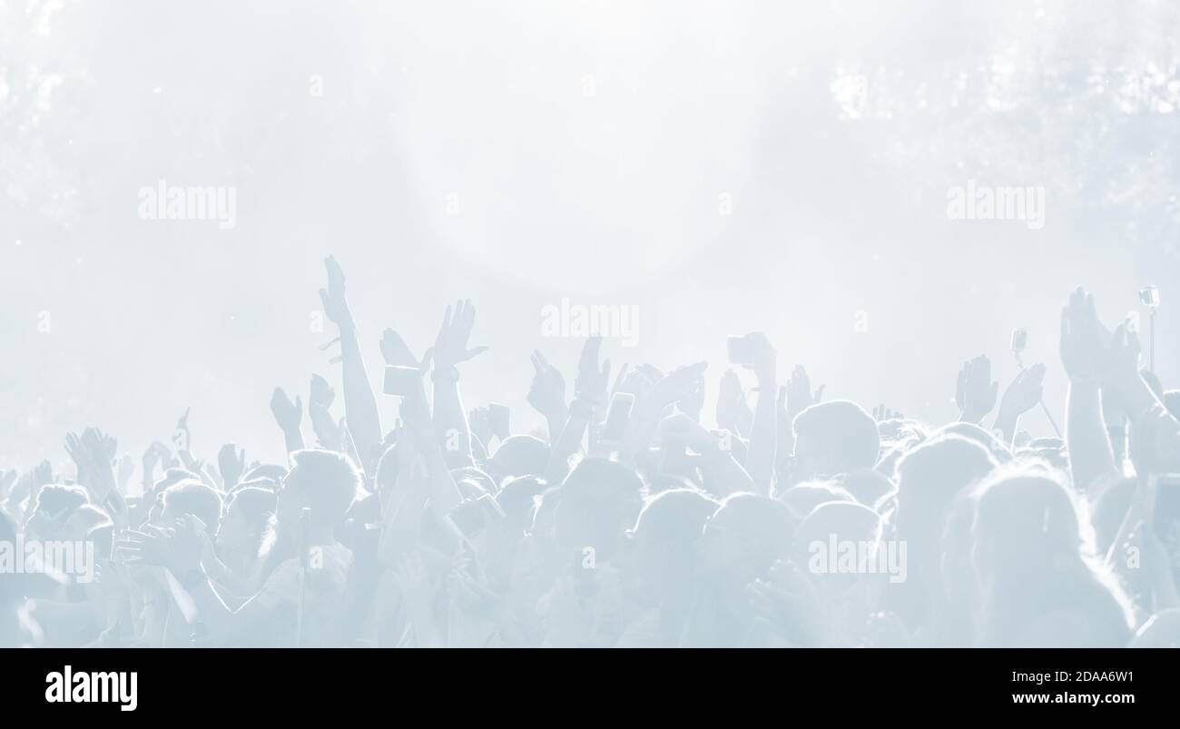 Crowd of spectators at a concert in light blue tonality. High key ...