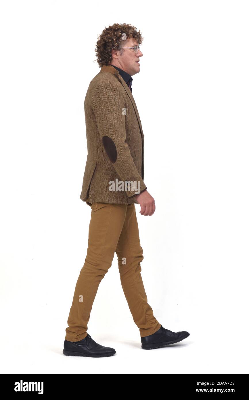 side view of middle aged man with blazer walking on white background ...