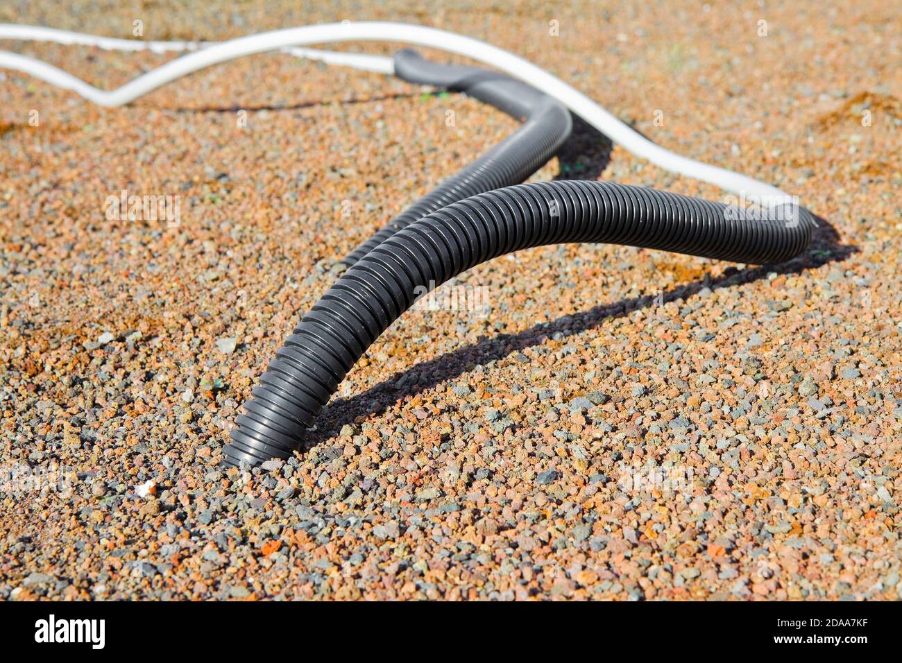 Corrugated pipe with cable coming out from the ground Stock Photo - Alamy