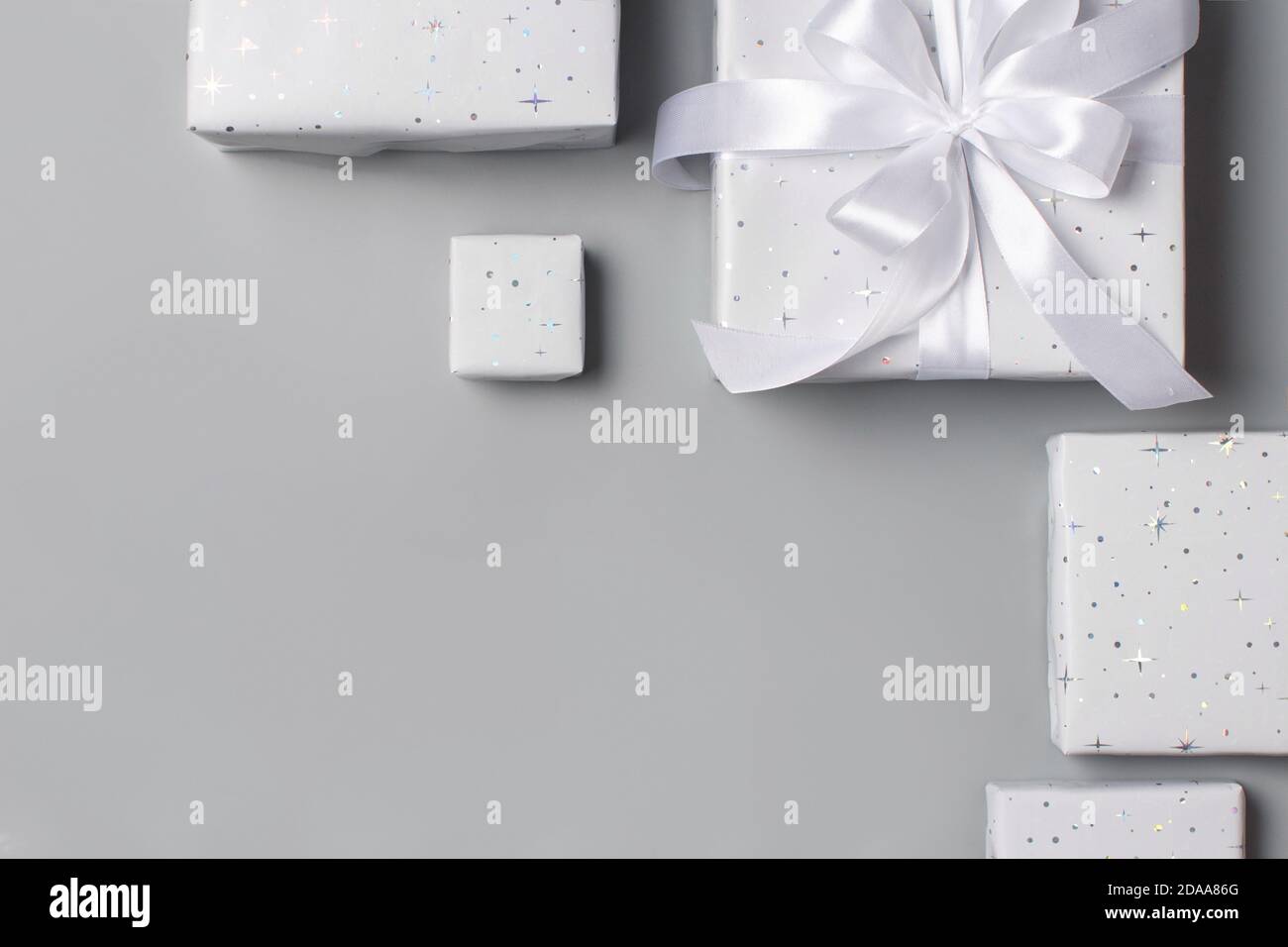 Wrapped grey Gift boxes with white ribbon on grey top view with copy ...