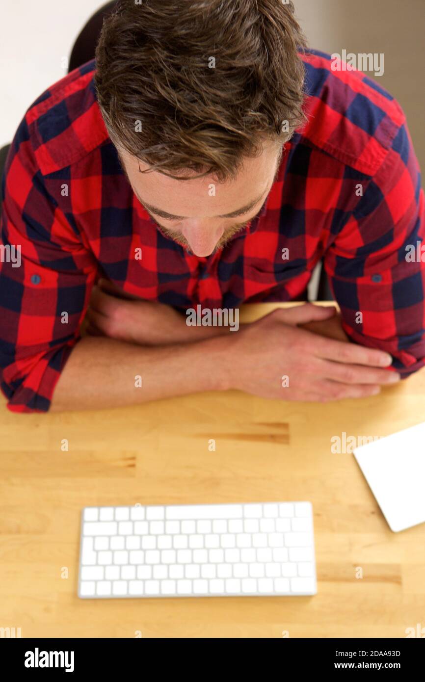 Aerial portrait of man sitting at desk with keyboard thinking Stock ...