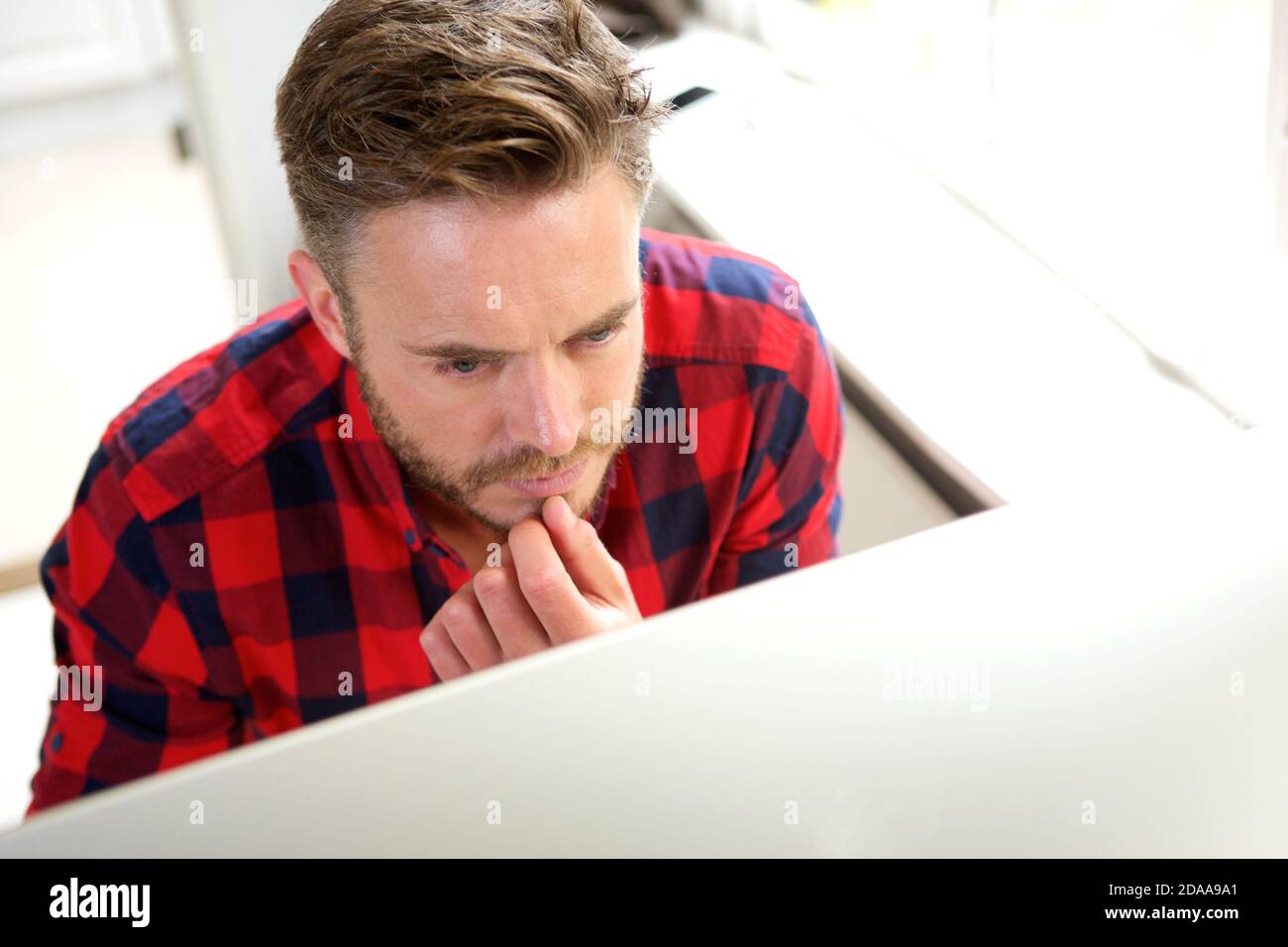 Portrait of attractive business man thinking behind computer screen ...