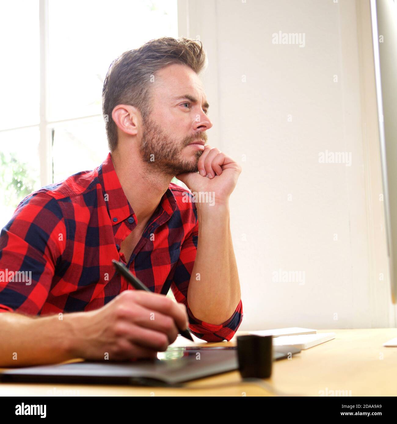 Side profile portrait of man thinking sitting at desk with stylus Stock ...
