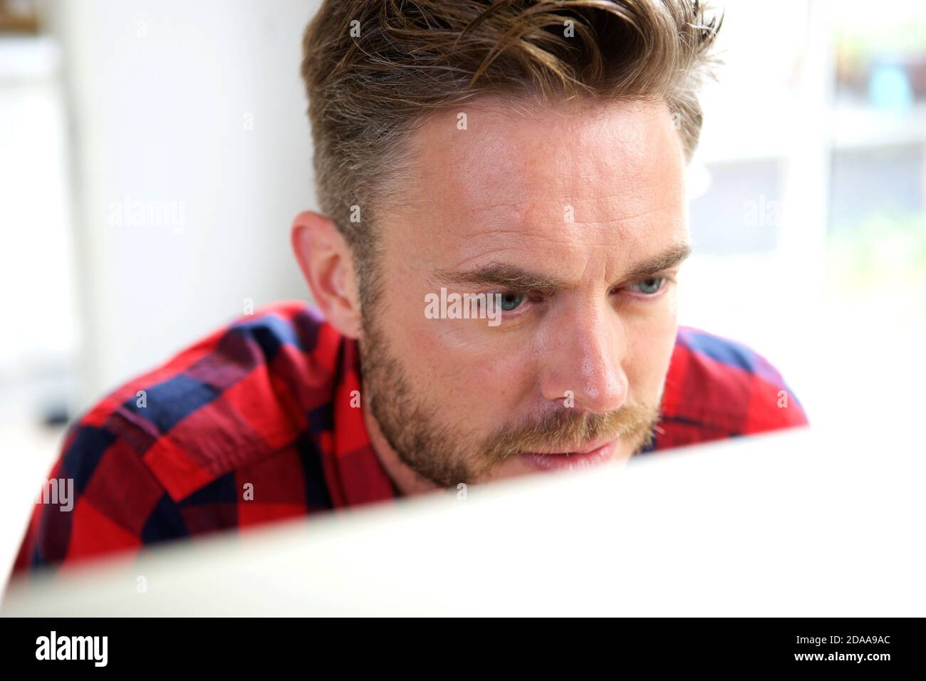 Close up portrait of handsome man working behind computer screen Stock ...