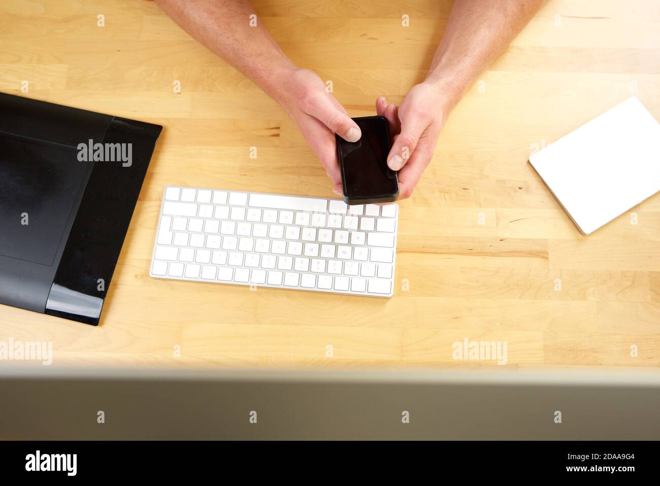Aerial portrait of hands holding cellphone by keyboard on desk Stock ...