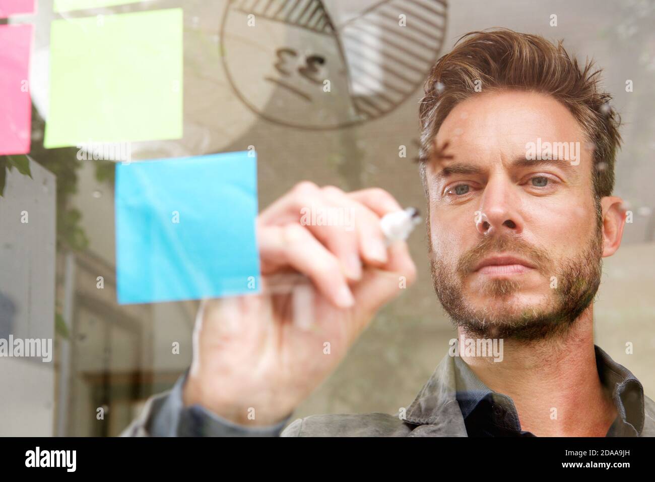 Portrait of handsome man writing on transparent idea board thinking ...