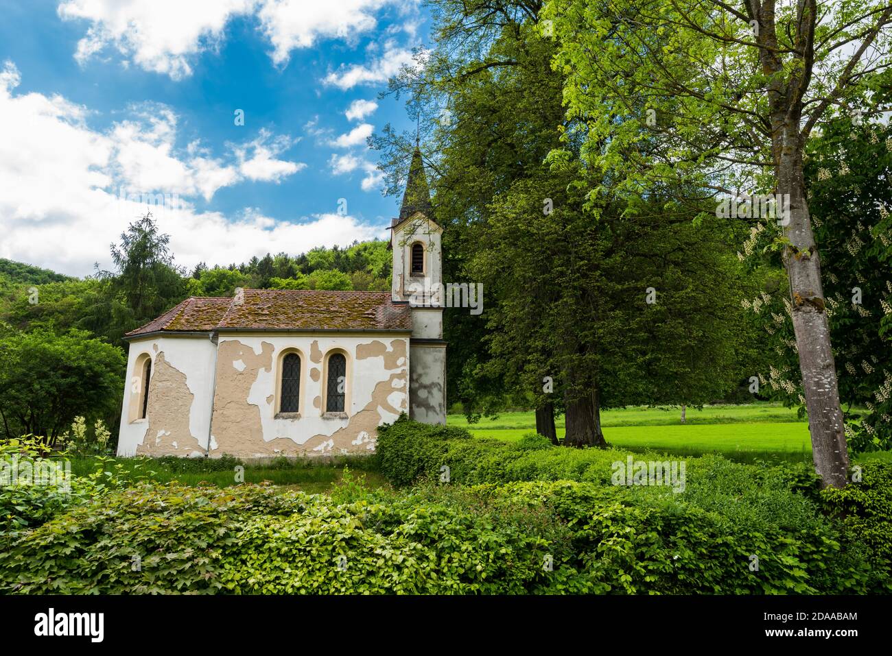 Small withered chapel in Bavaria standing amidst trees in summer with ...