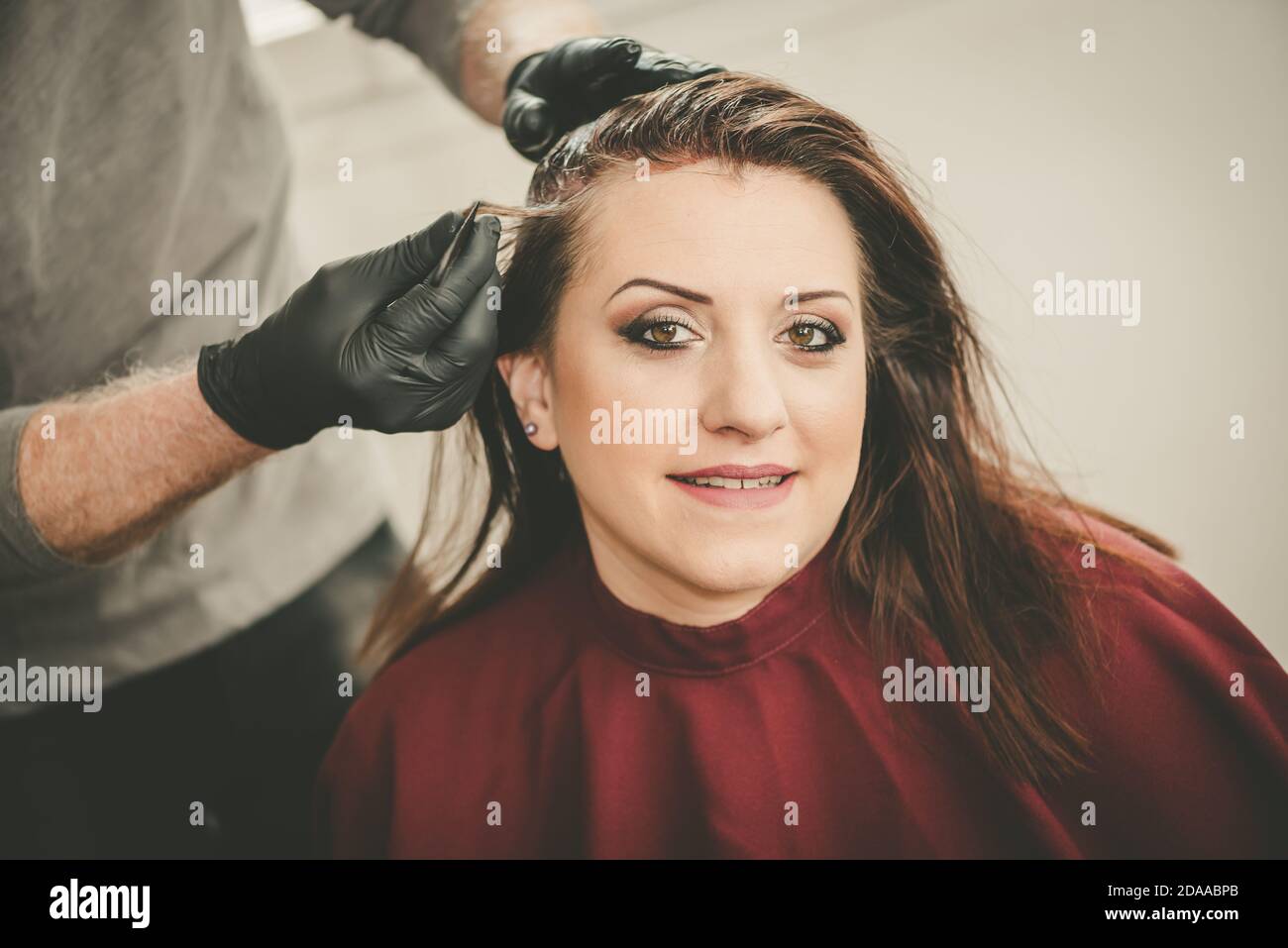 Hairdresser coloring female client hair Stock Photo - Alamy