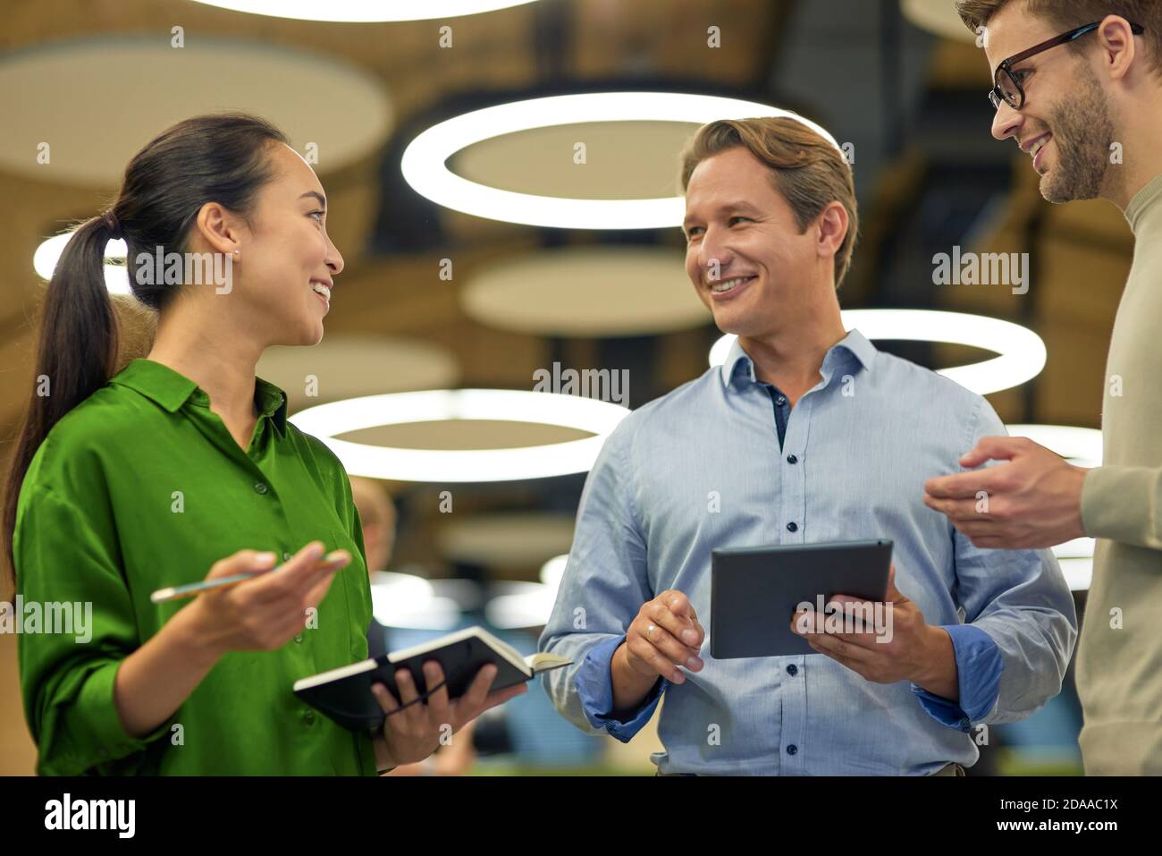 Tree positive colleagues using digital tablet and discussing something ...