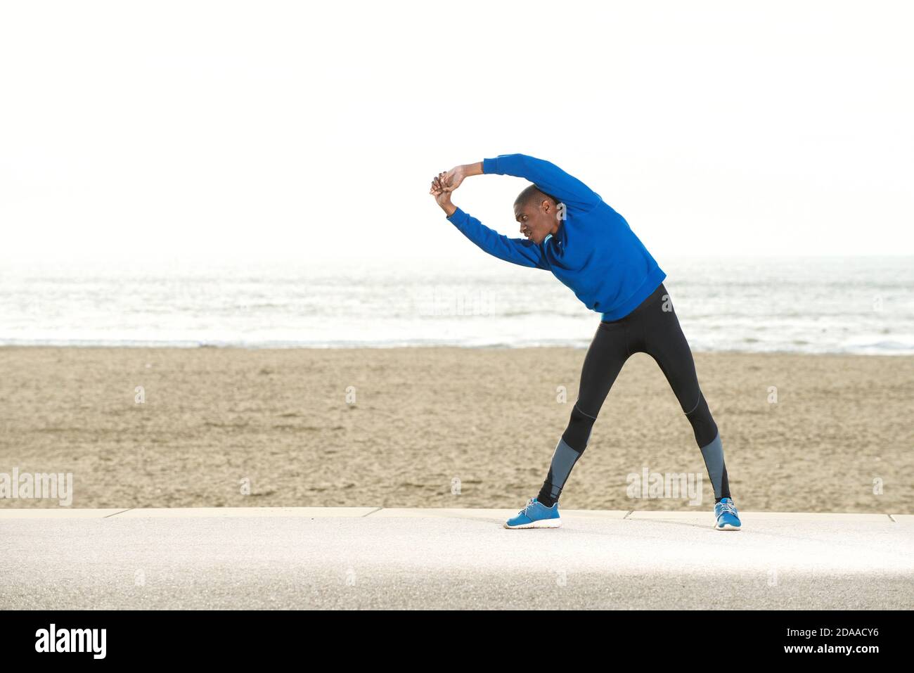 Portrait of young sporty guy stretching exercise at the beach Stock ...