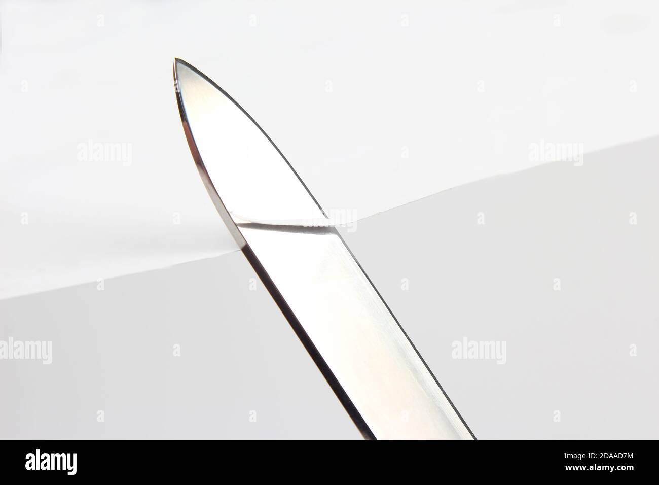 the blade of a sharp knife cut across the white paper Stock Photo - Alamy